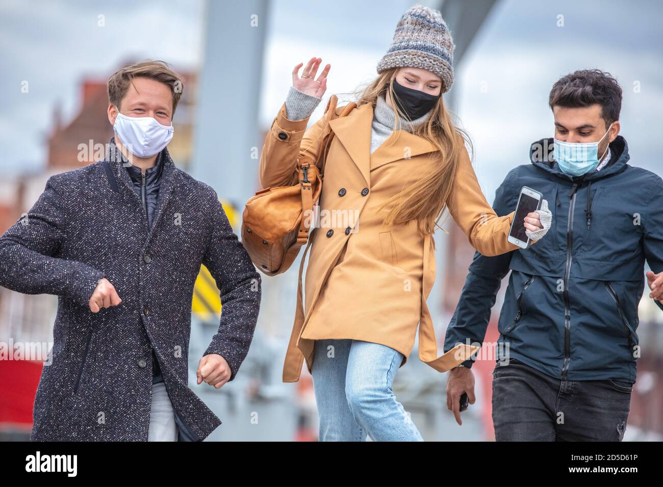 Zwei Männer und eine Frau in Corona-Zeit, mit alltäglichen Masken, in ...
