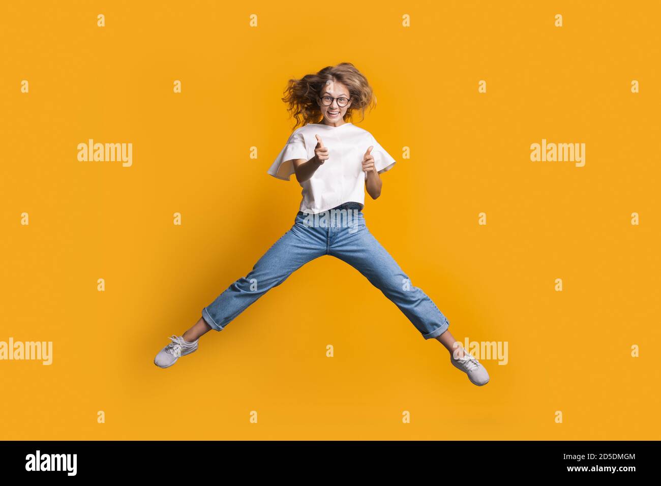 Jumping blonde woman is gesturing the shot and gun with both hands ...