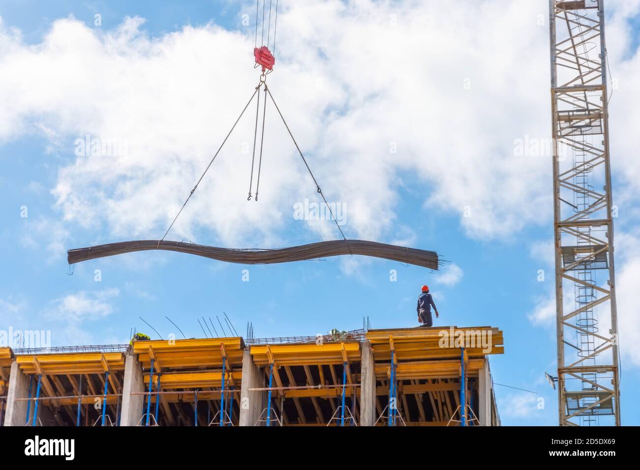 A construction crane lifts a load of metal reinforcement to the upper ...