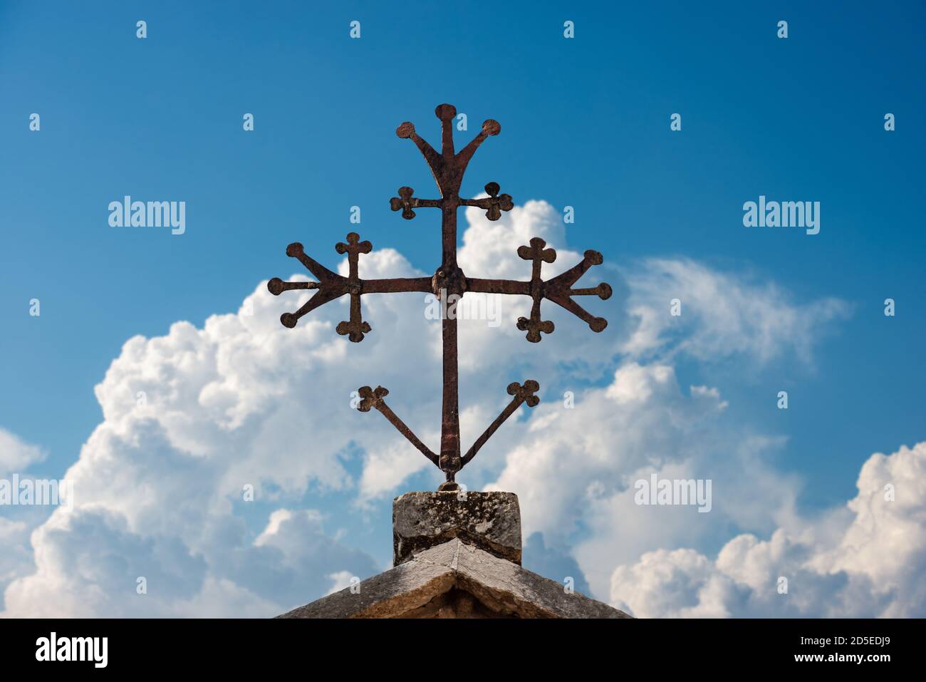 Medieval Christian cross in wrought iron on a blue sky with clouds ...