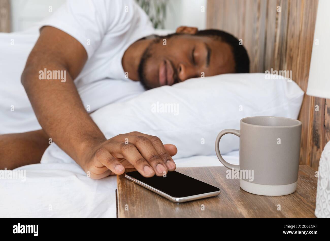 African Man Sleeping Through Alarm-Clock On Phone Lying In Bedroom ...