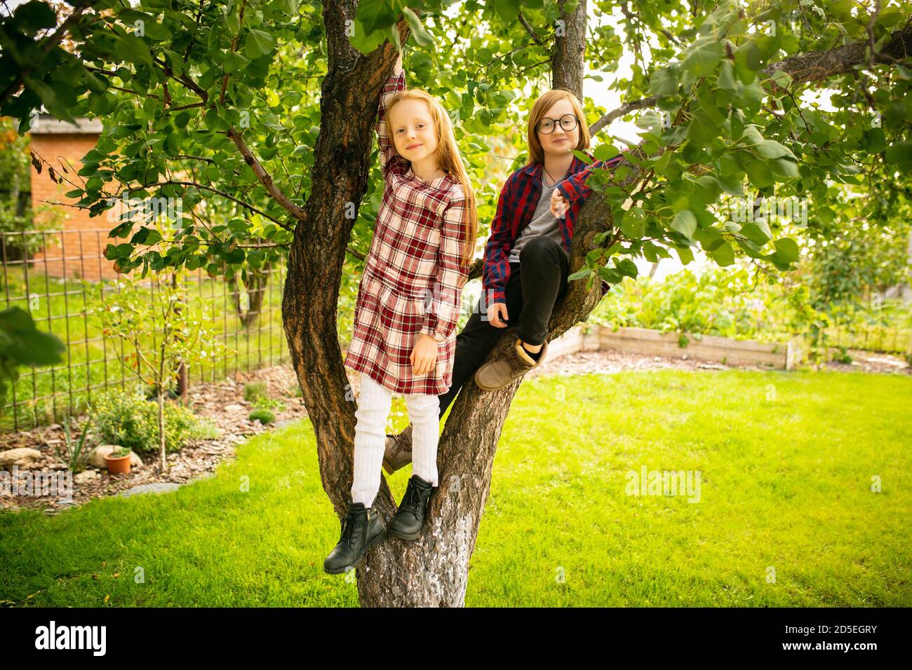 Careless. Happy brother and sister playing in a garden outdoors ...