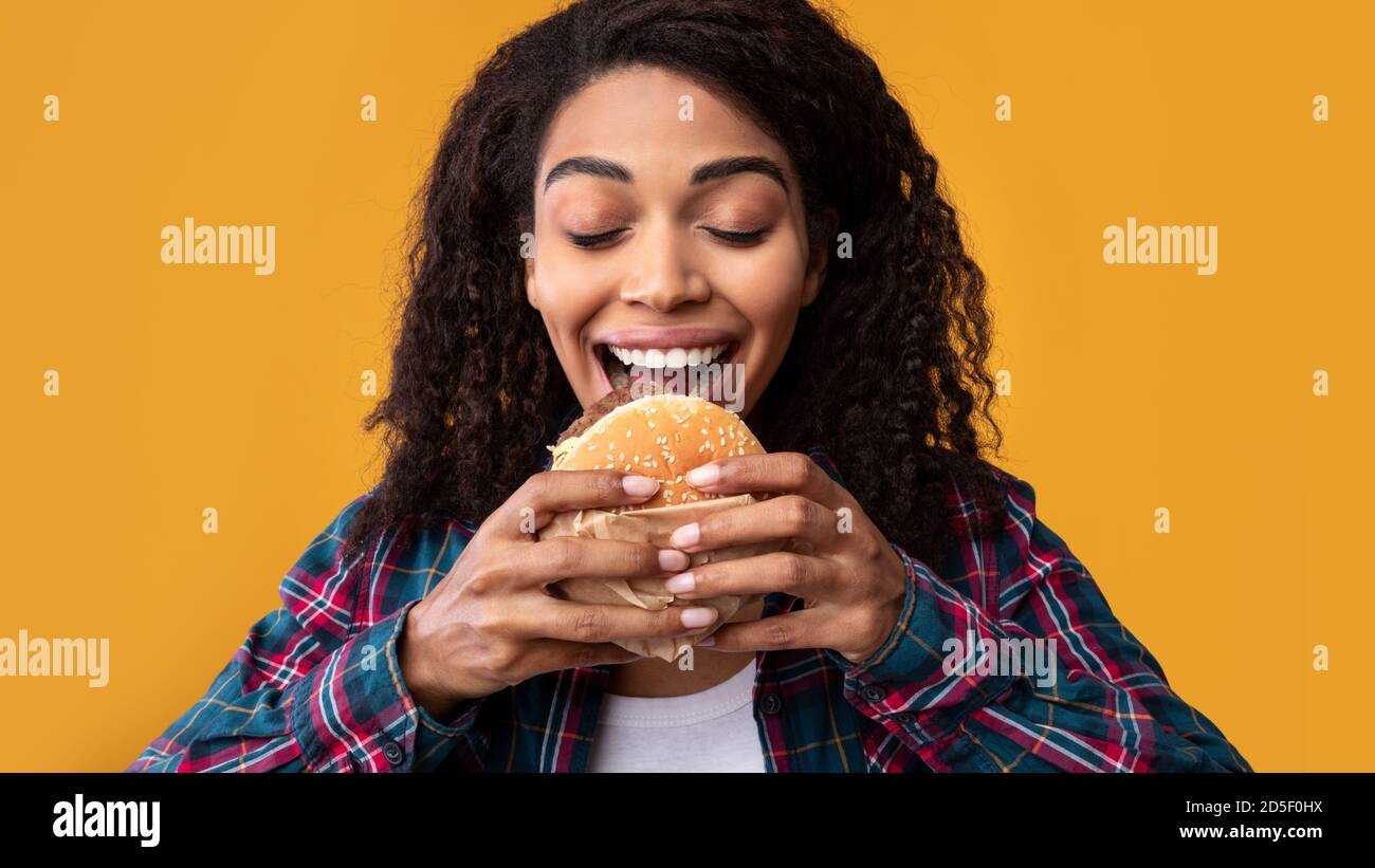 Hungry African American Lady Eating Burger At Studio Stock Photo - Alamy