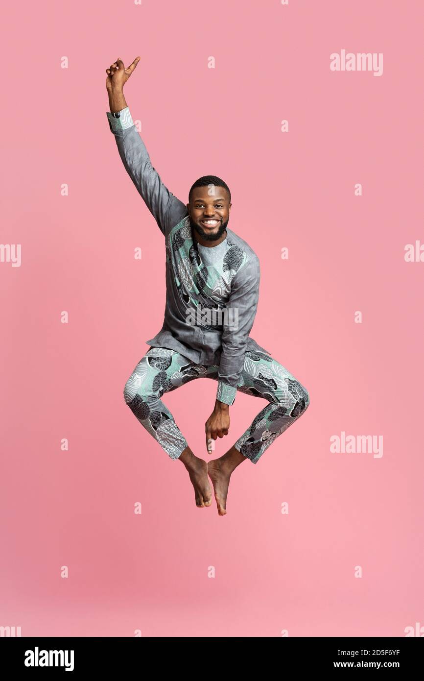 Excited black man jumping up over pink background Stock Photo - Alamy