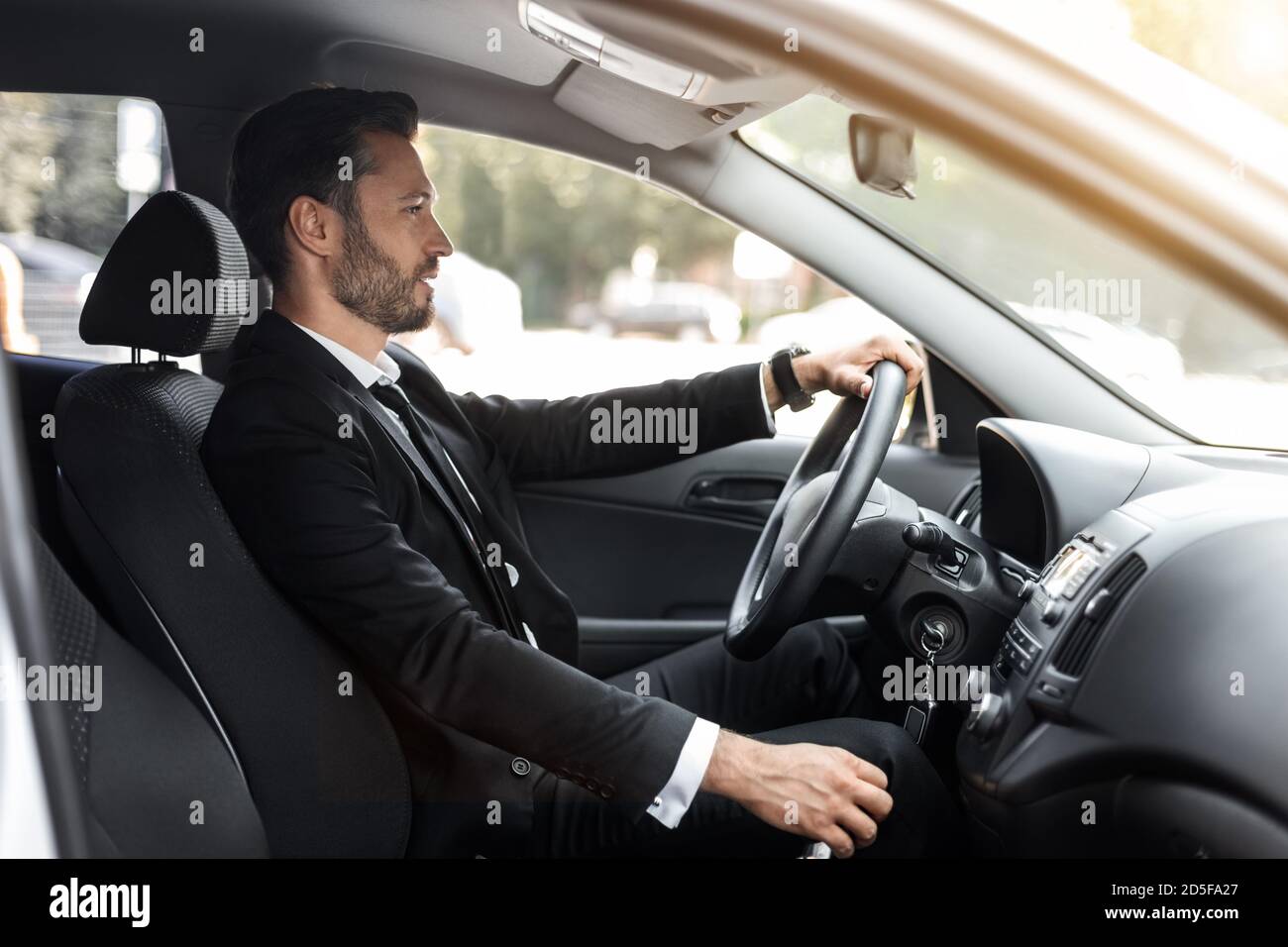 Handsome businessman driving car to airport, going on business trip ...