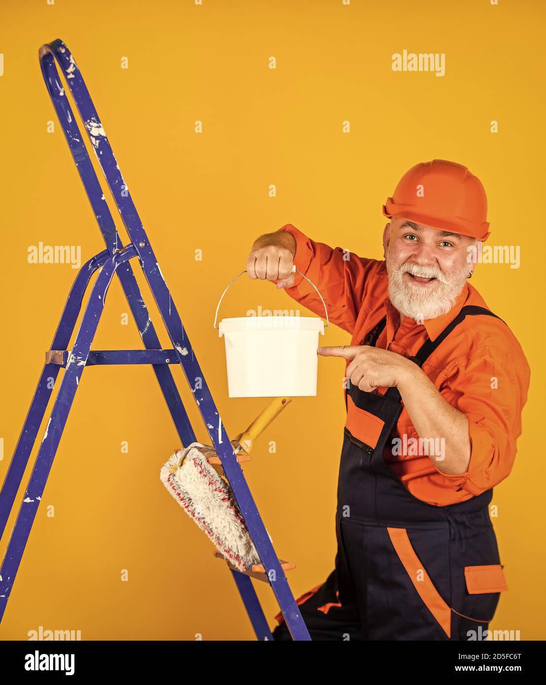 painter in overall and cap with paint bucket. builder worker painting ...