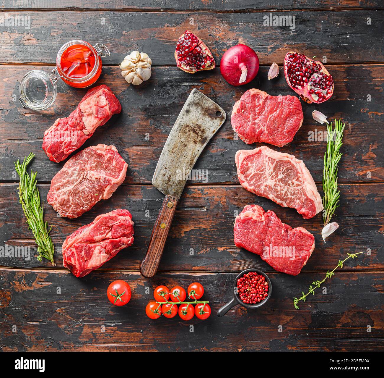 Butcher meat cleaver in frame of beef steaks over old wood dark table ...