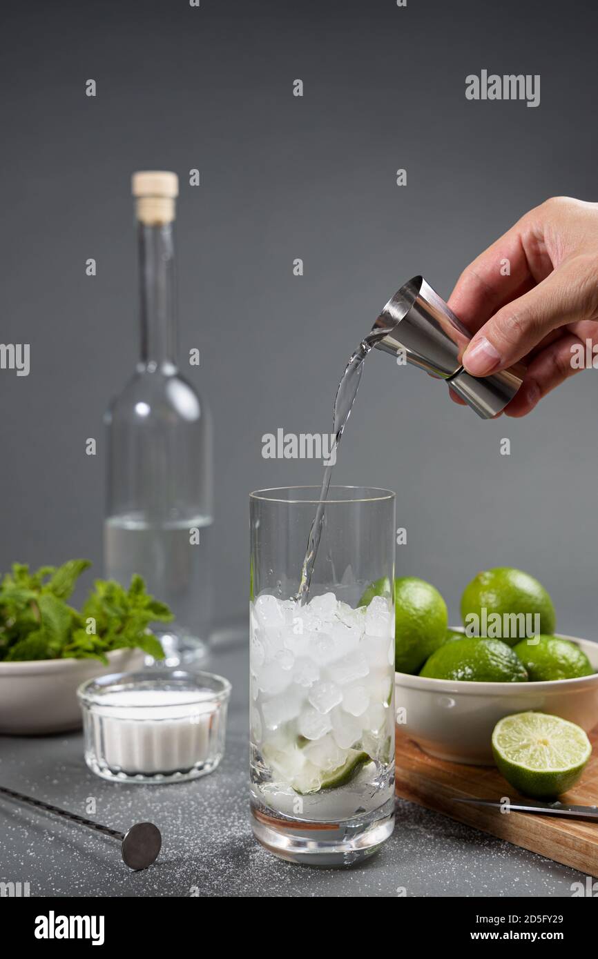 Mojito cocktail preparation. Man's hand pouring rum with a jigger into ...