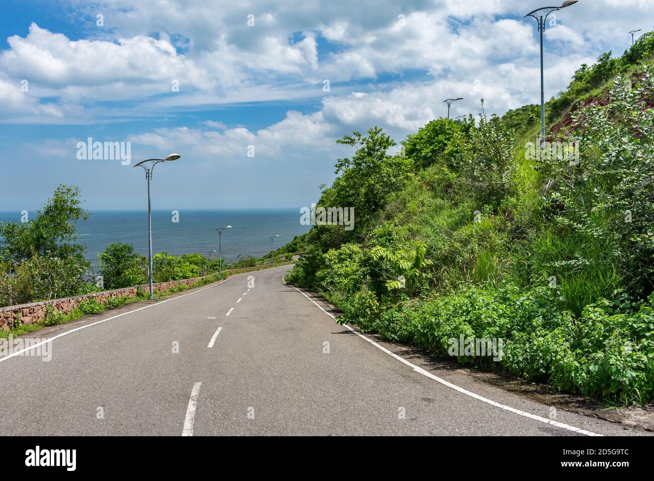 straight road going to downwards down of a mountain with blue ocean ...