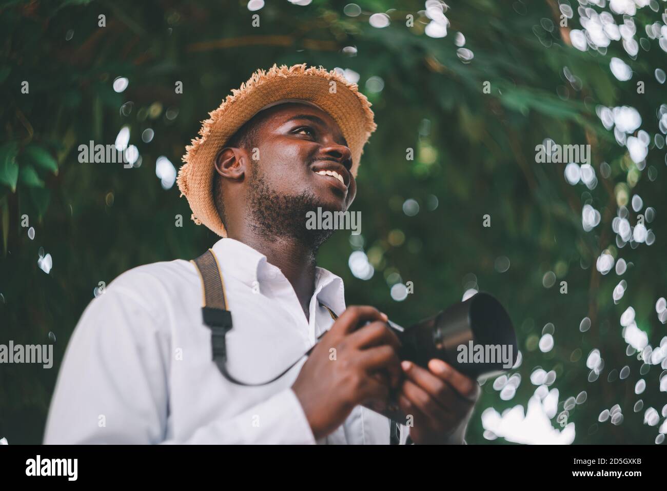 African man photographer holding a camera in the green nature ...