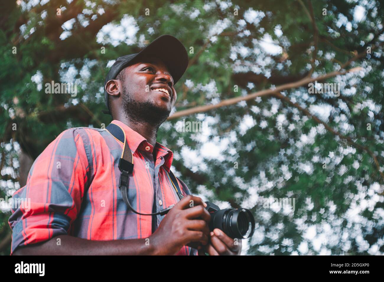 African man photographer holding a camera in the green nature ...