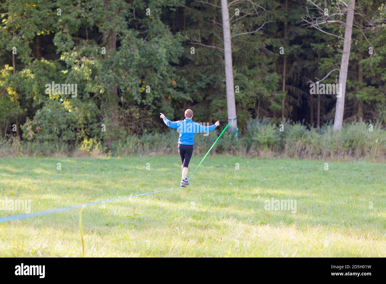 Man walking, jumping and balancing on rope in park Sports a tightrope ...