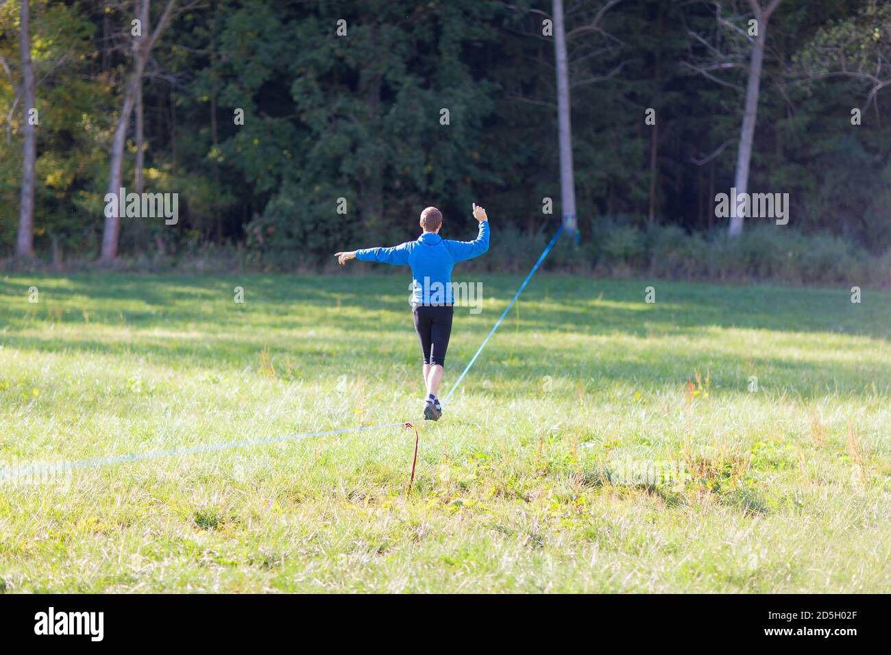 Man walking, jumping and balancing on rope in park Sports a tightrope ...