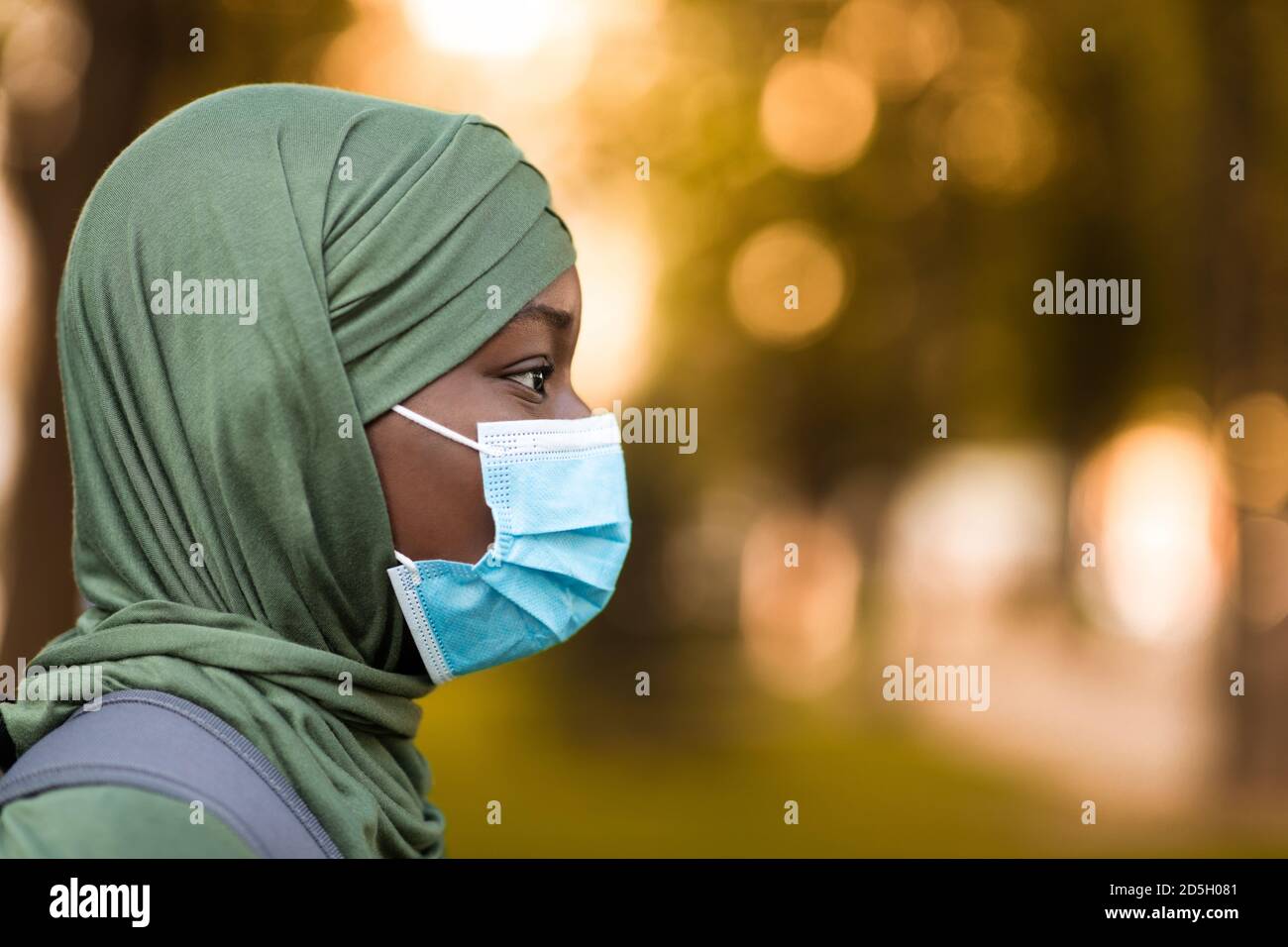 Profile of black muslim woman wearing medical mask and hijab standing ...