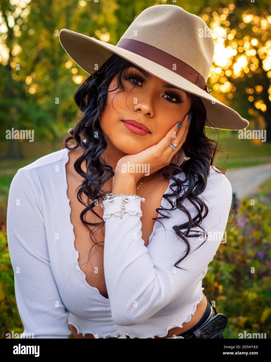 Young Latina woman is wearing a hat outdoors during sunset Stock Photo ...