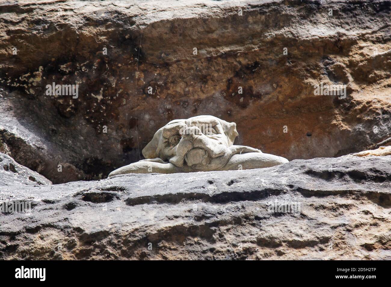 Rocky gap with stone monster looking out Stock Photo - Alamy