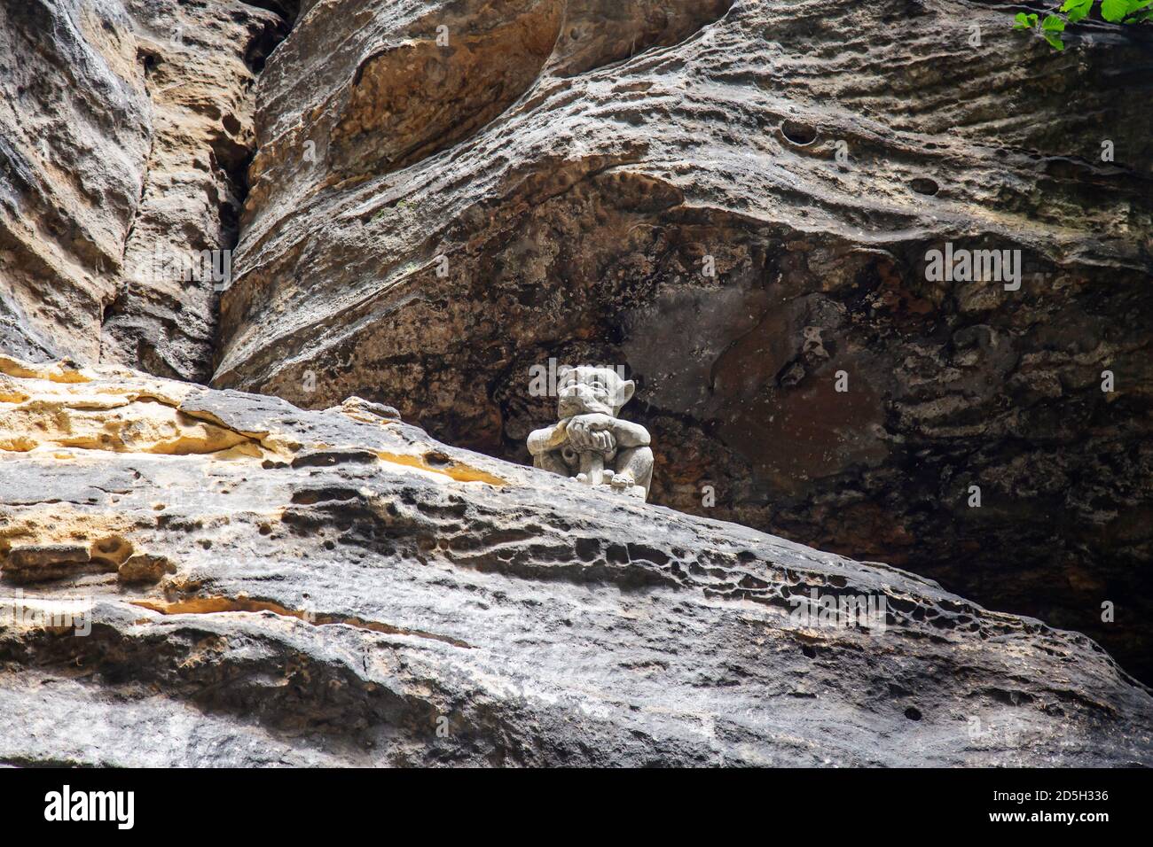 Rocky gap with stone monster looking out Stock Photo - Alamy