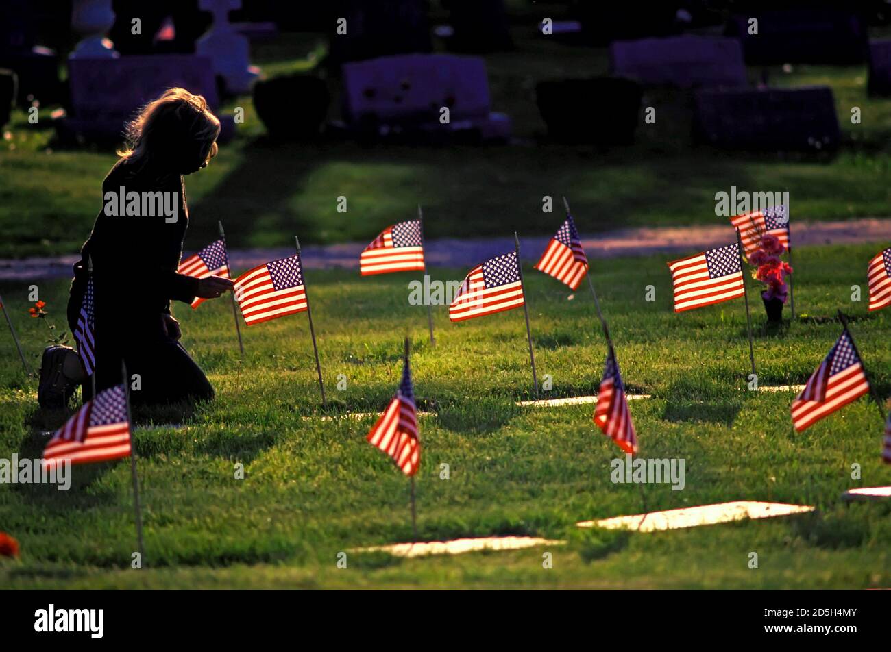 Woman pays respect at a grave site on memorial day with American flags ...