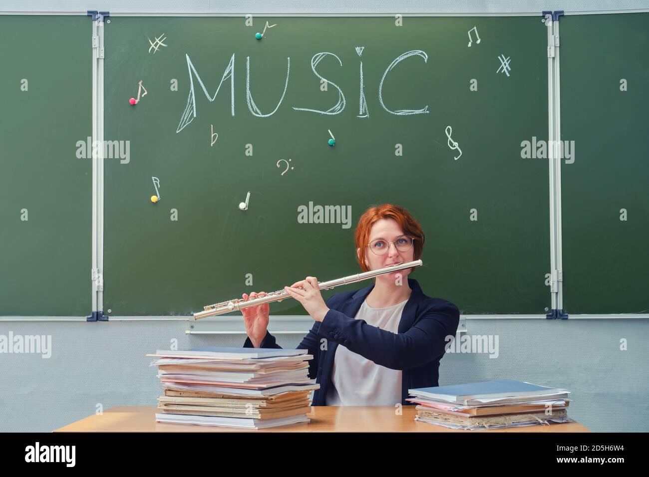 School music teacher plays the flute in the classroom. Woman teaches ...