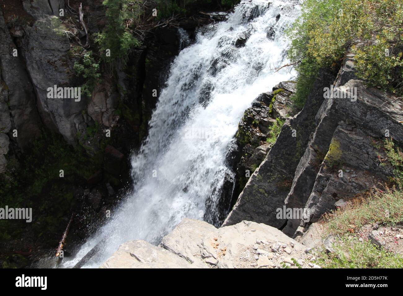 Low waterfall with white foam in the forest with cliffs and greenery ...