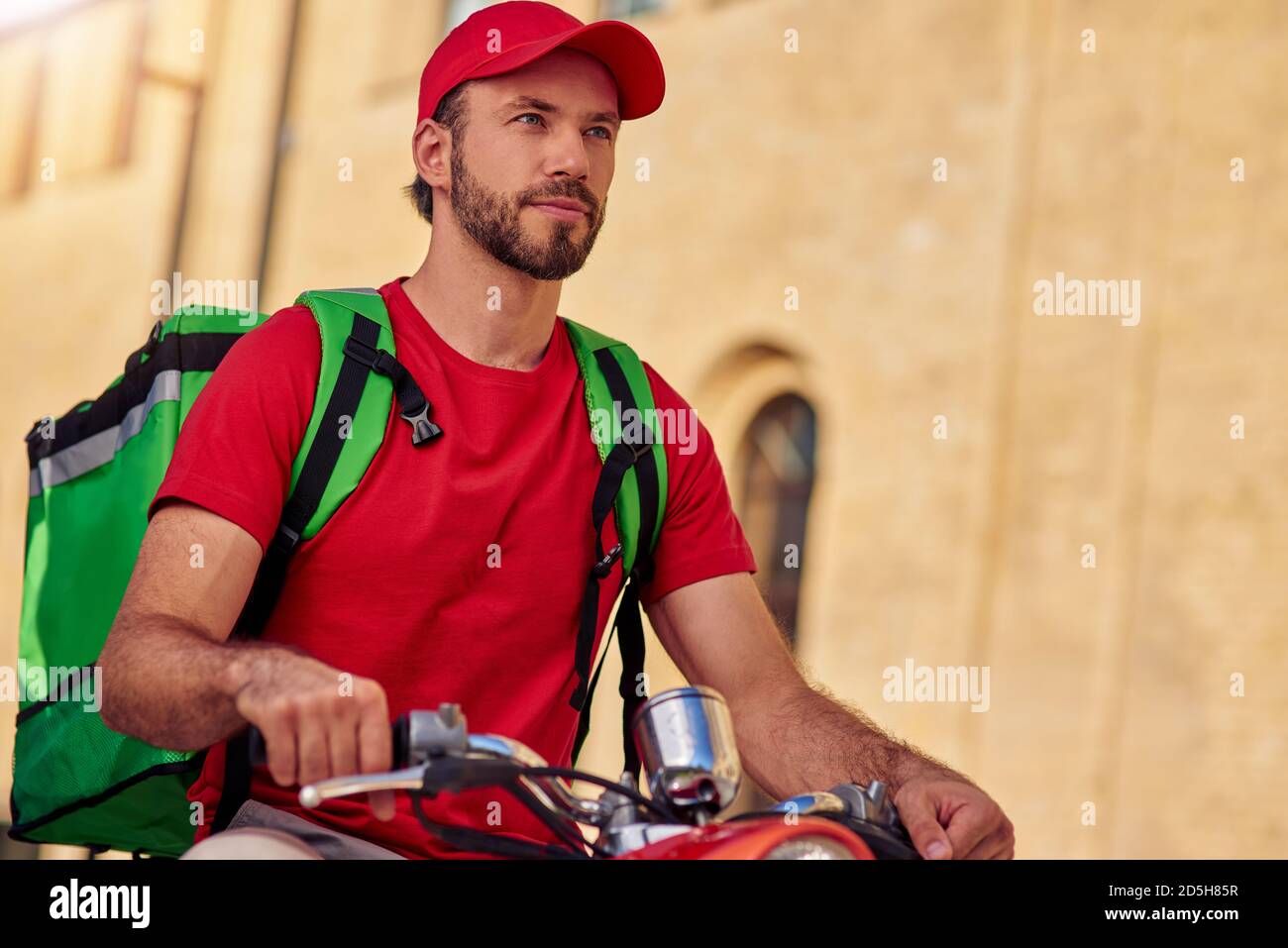 Portrait of young caucasian delivery man in red uniform with ...