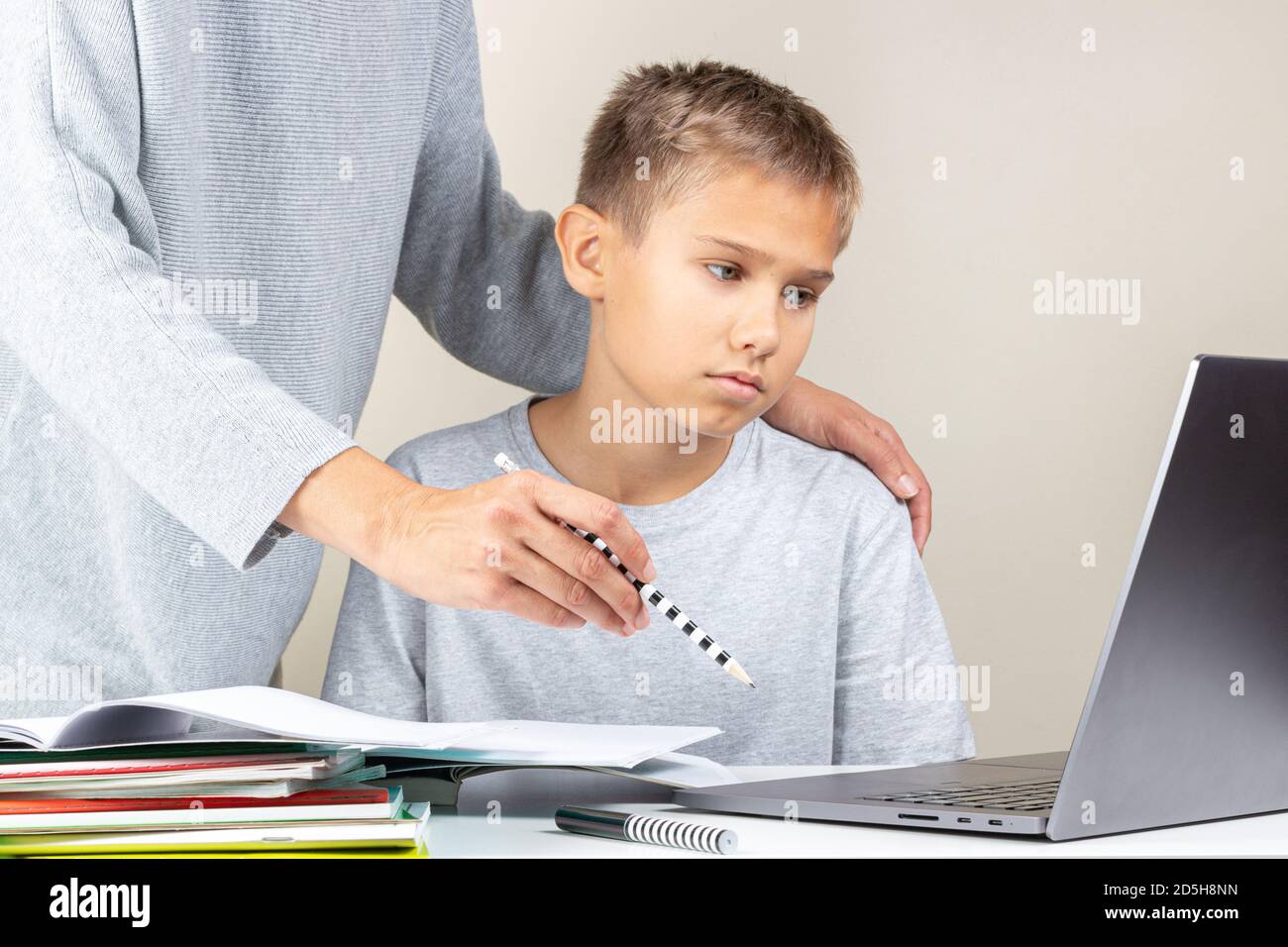 Kid learning online with laptop computer at home. Mother help him ...