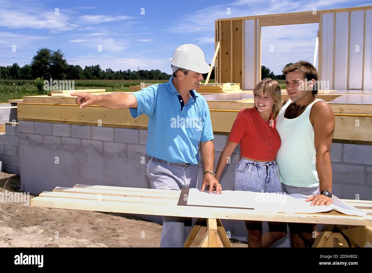 Male contractor discusses home plans with a young married couple Stock ...