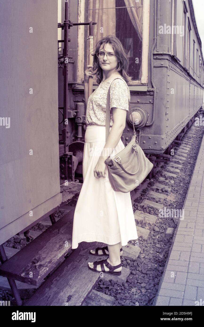 A girl stands on the steps of the cars train. Historical monochrome ...