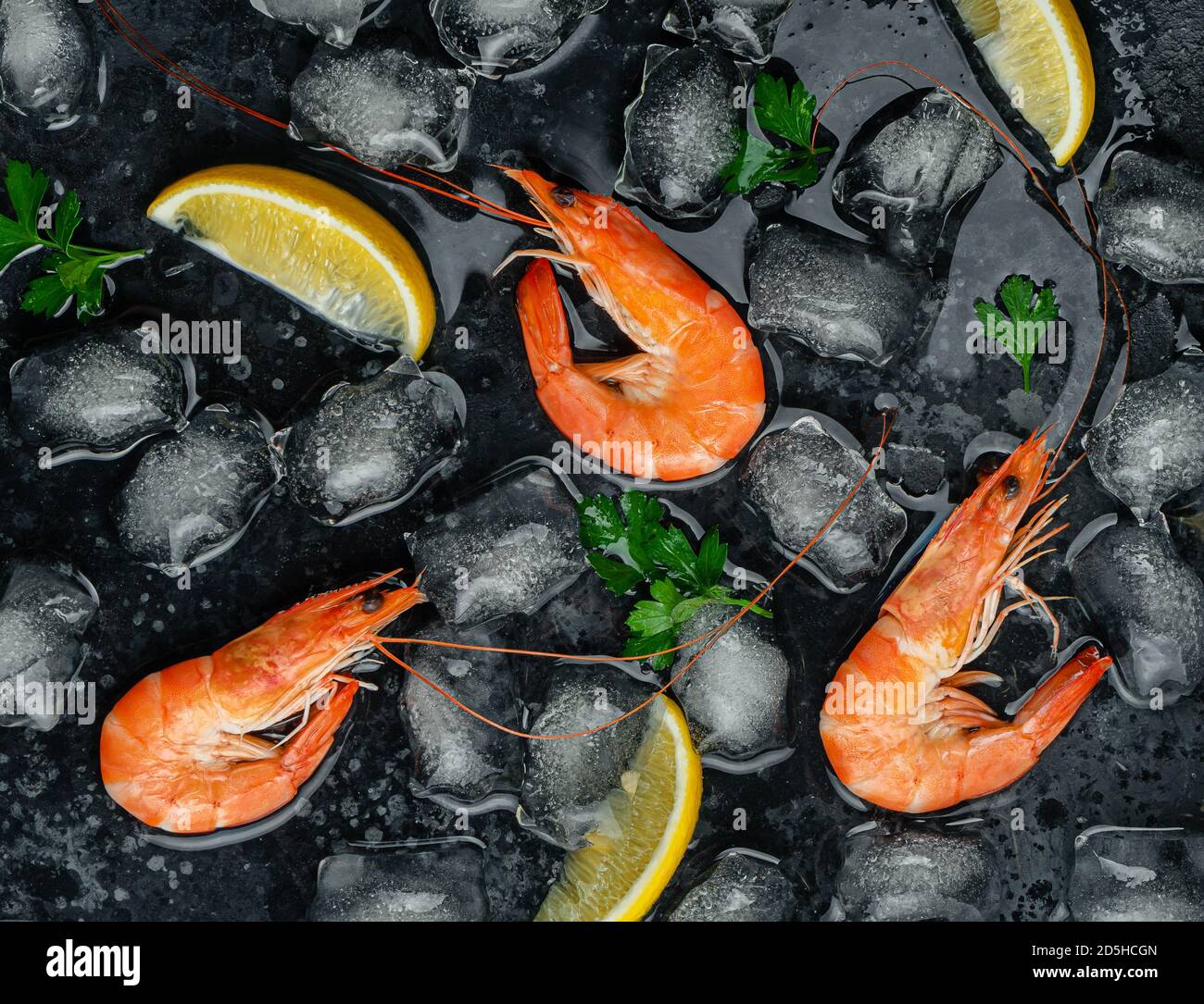 Tiger shrimps with ice, lemon and parsley. Food background. Flat lay ...
