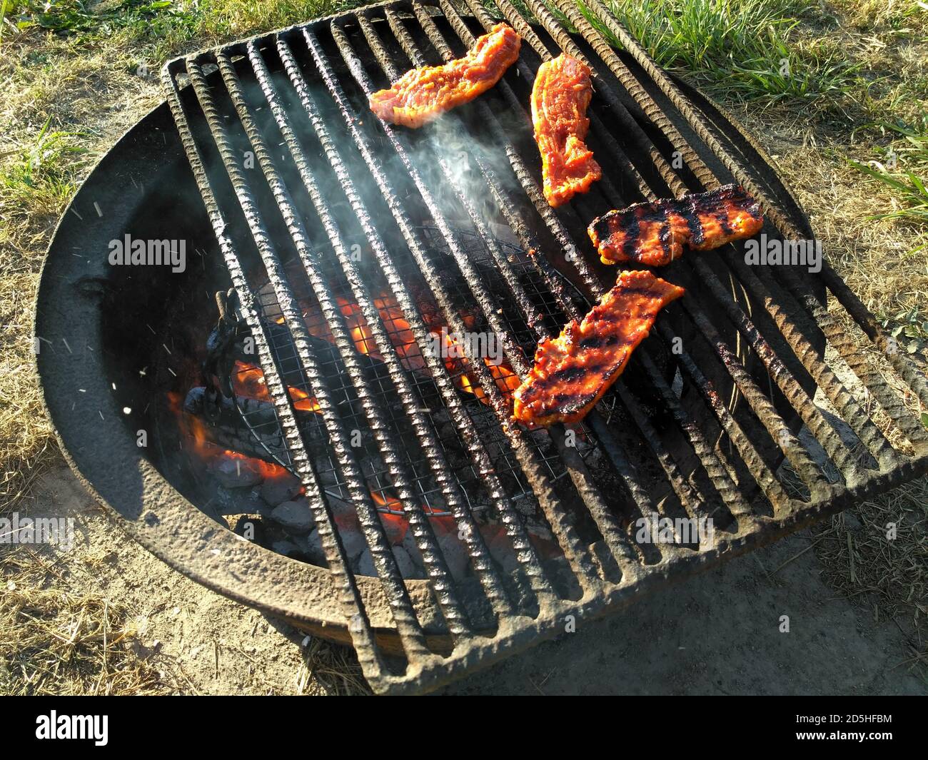 Marinated pork cooking over a campfire on a metal grill Stock Photo - Alamy