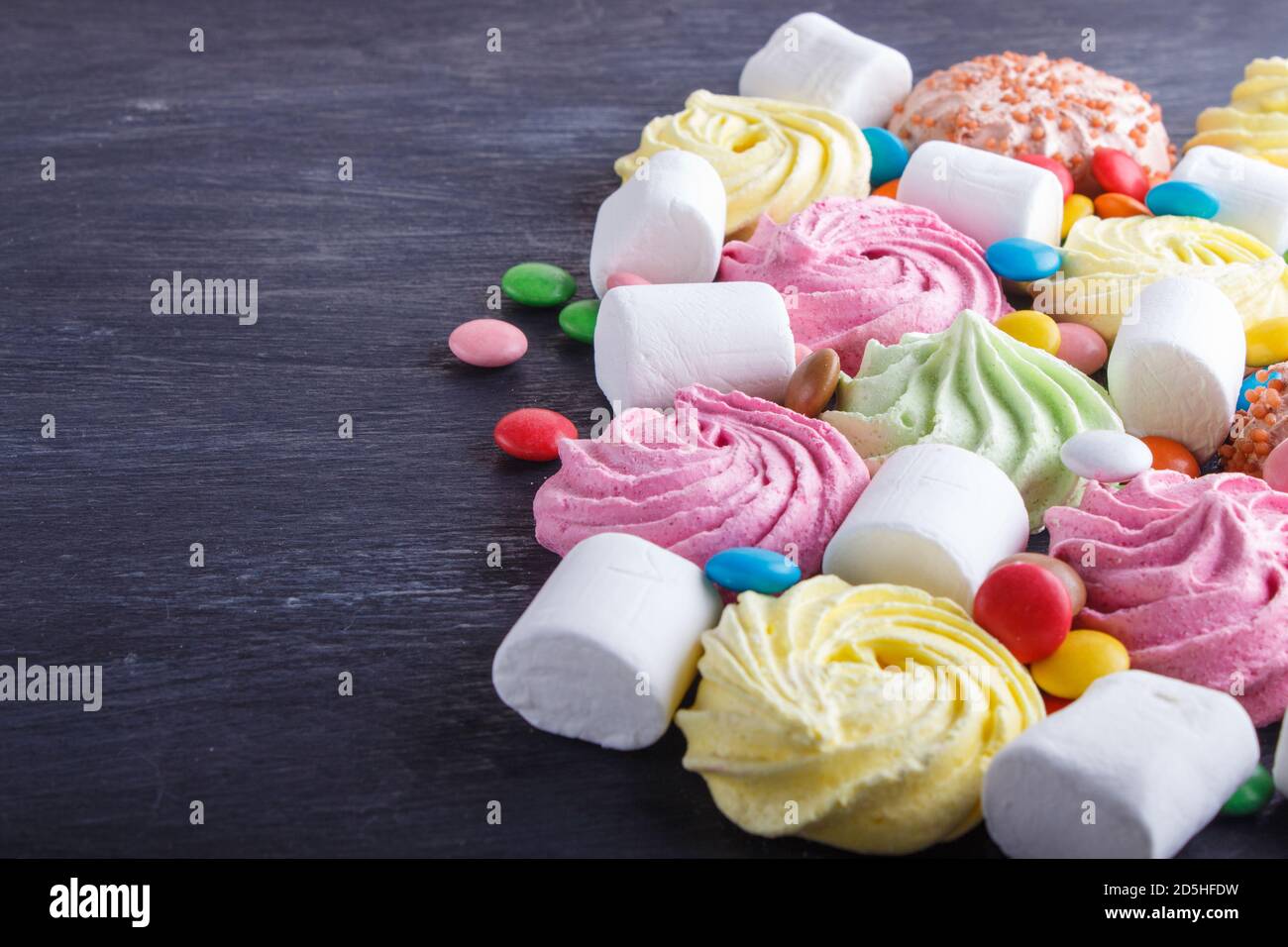 mixed multicolored candies on black wooden background. copy space, top ...
