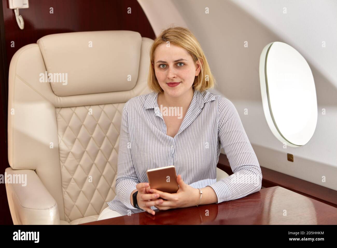 A young woman sits in a passenger seat inside a private jet Stock Photo ...