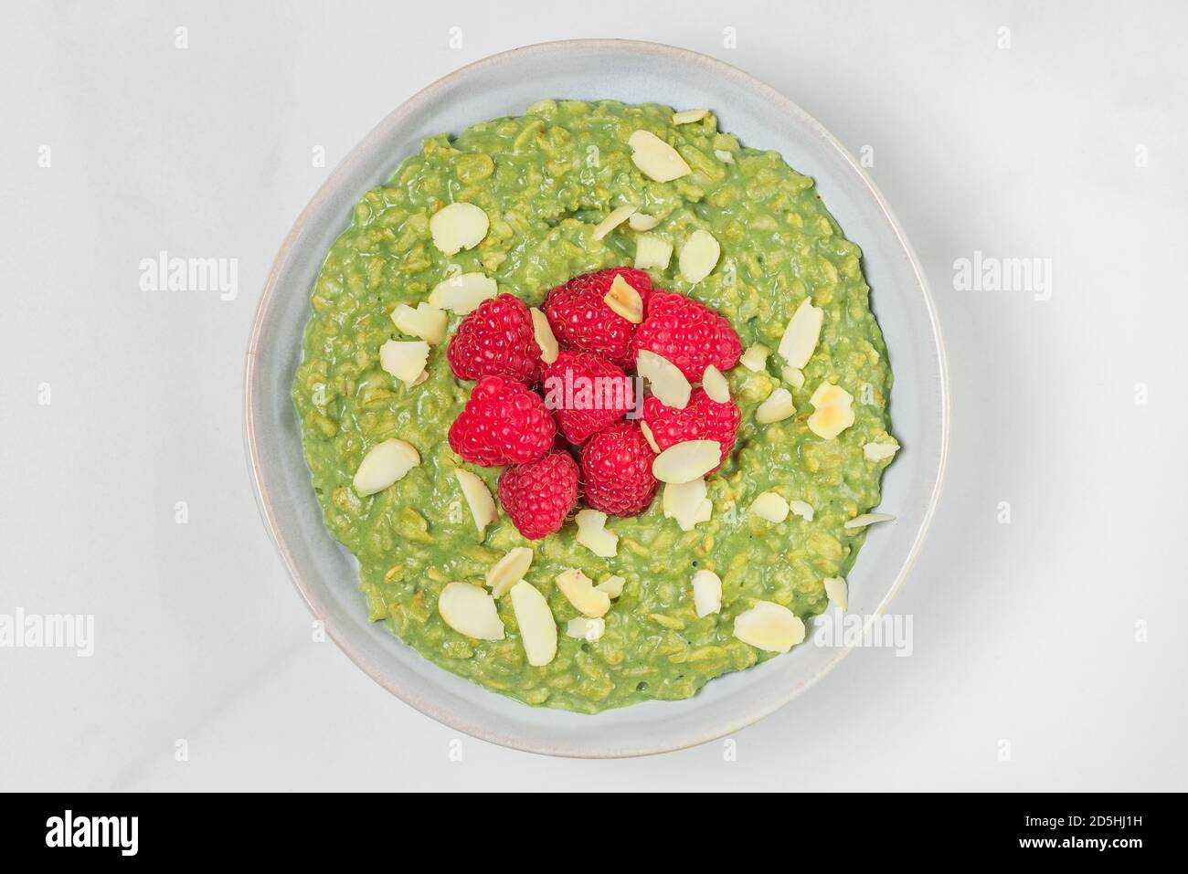 Matcha oatmeal porridge with raspberries and nuts in a bowl on white ...