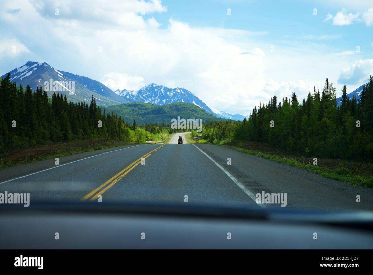 Looking out the front Car window, with pine trees, mountains, and roads ...