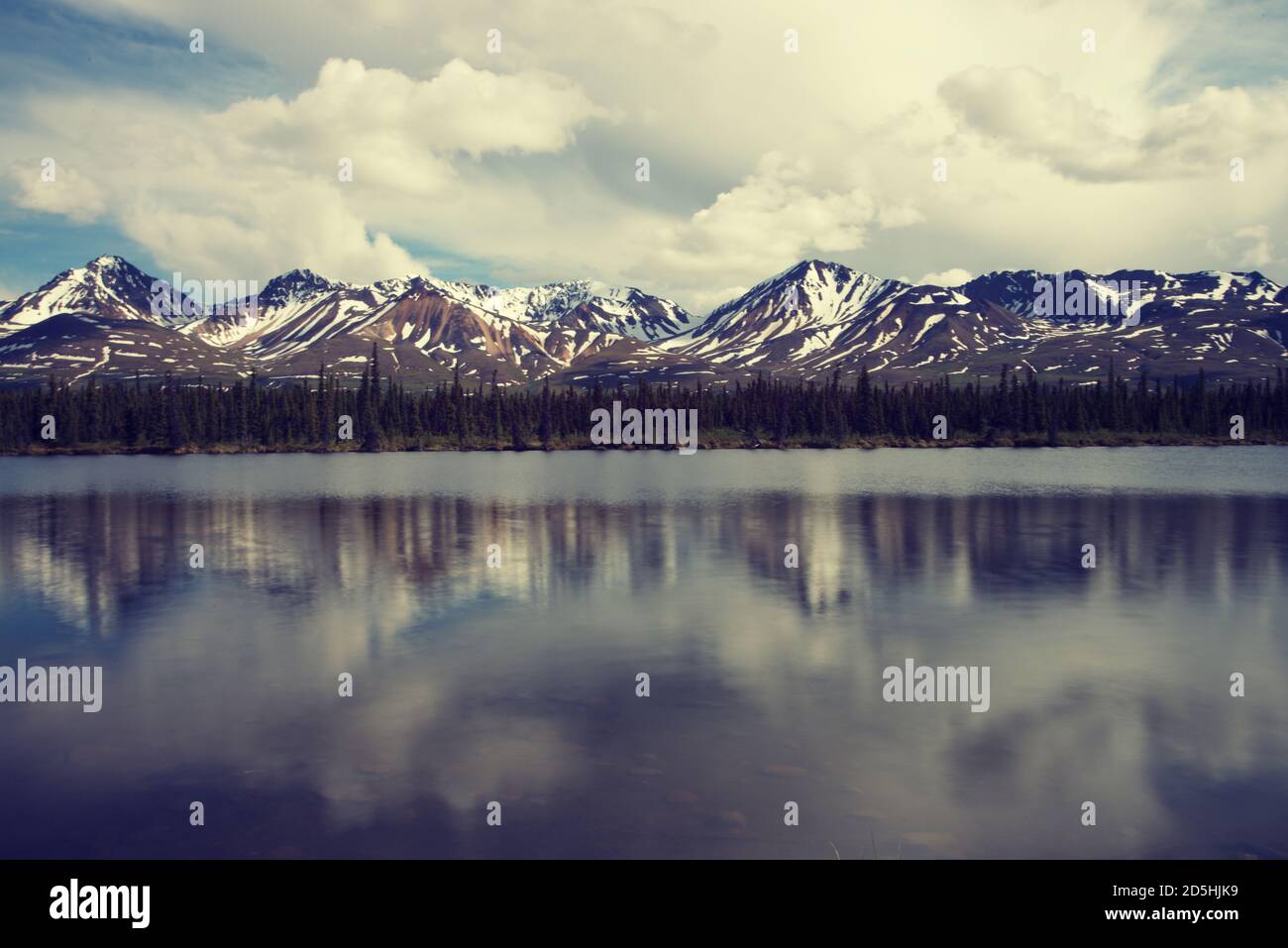 Jagged snowy mountain peaks with snow on the top reflected in a shallow ...