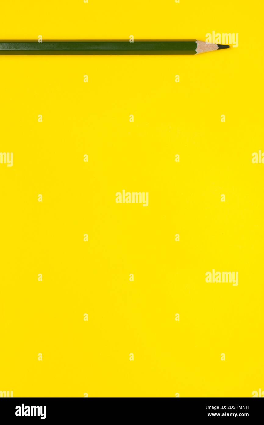 horizontal dark green sharp wooden pencil on a bright yellow background ...