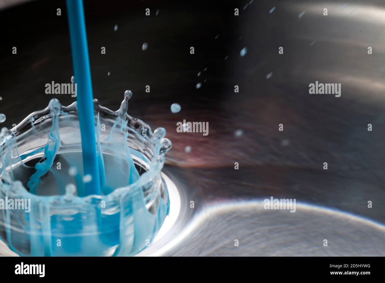 Blue paint splashing into water creating a crown splash and lots of ...
