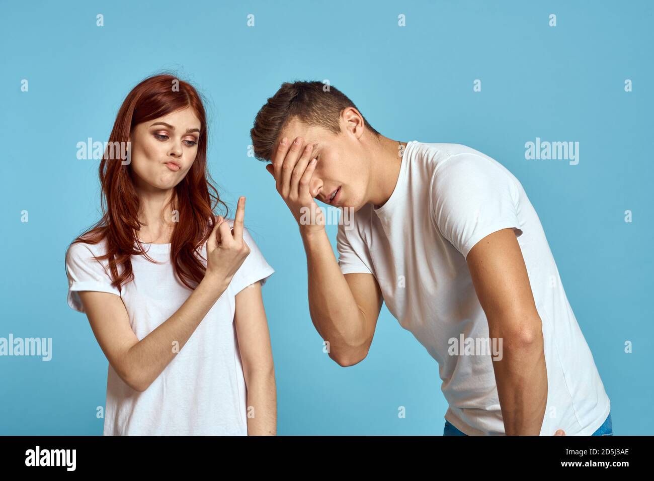 enamored man and woman in jeans and a T-shirt on a blue background hug ...