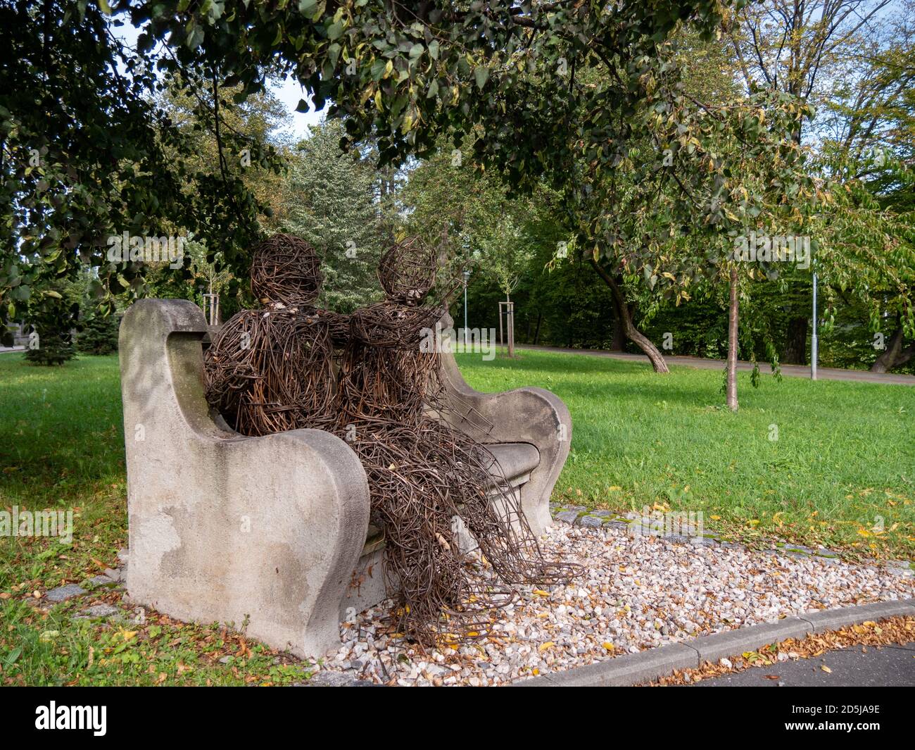 Sculptures made of wooden twigs, human figurines sitting on a park ...
