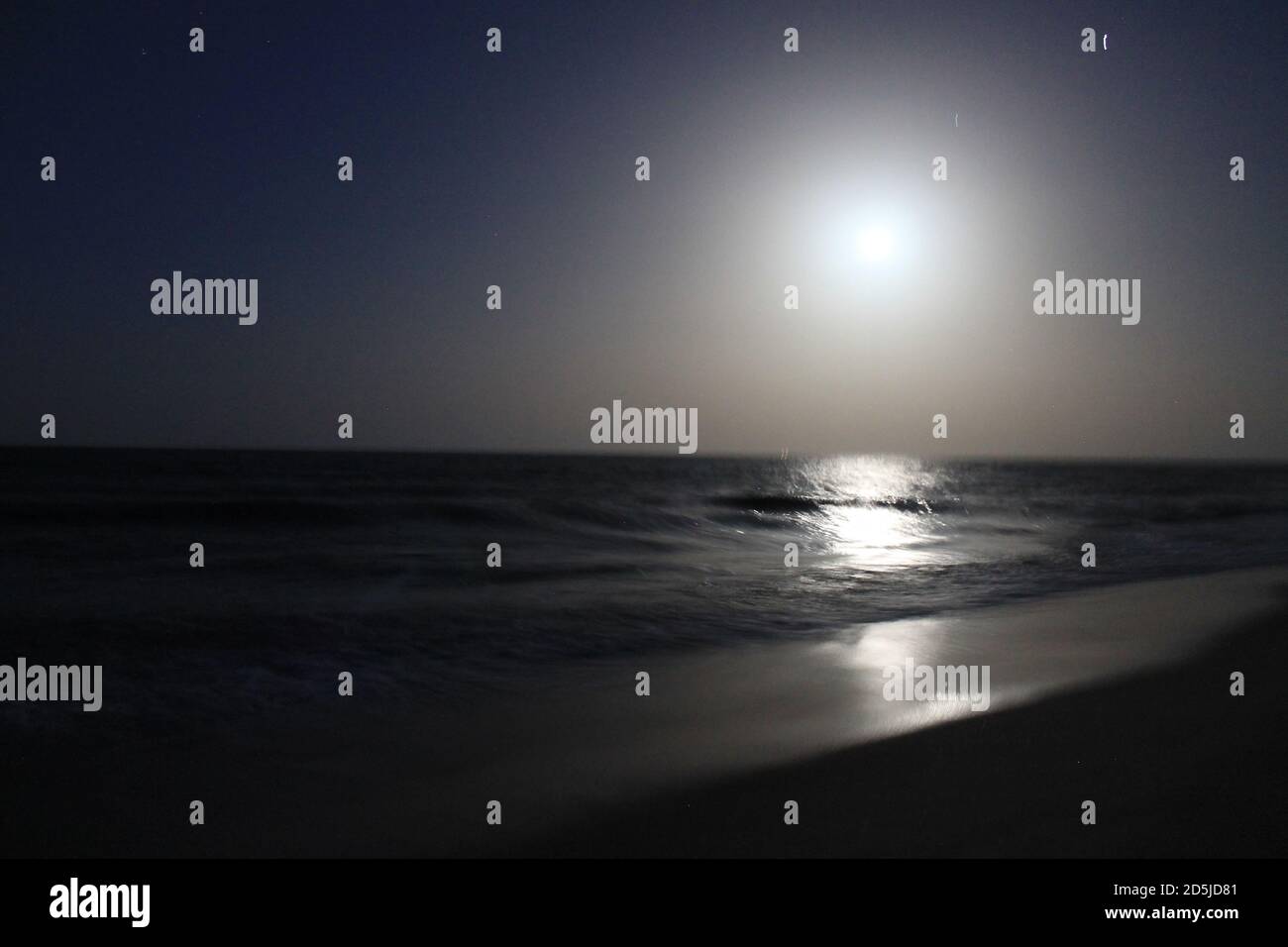 Moon rising over the ocean and causing a reflection back onto the water ...