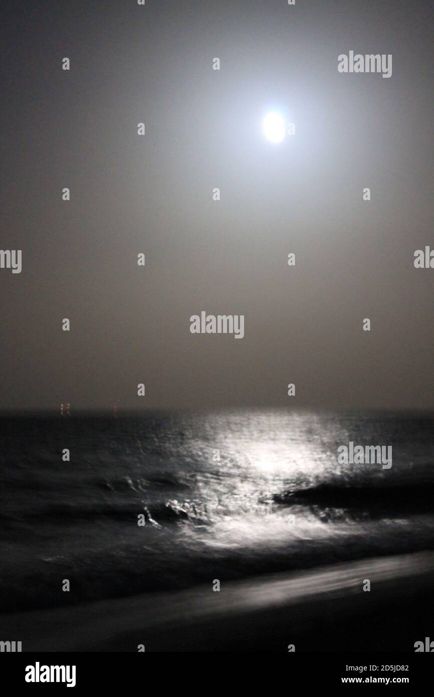 Moon rising over the ocean and causing a reflection back onto the water ...