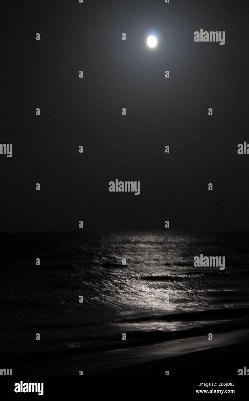 Moon rising over the ocean and causing a reflection back onto the water ...