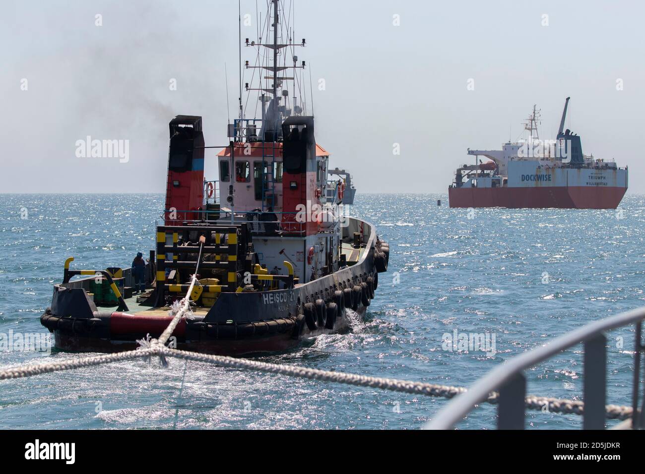 A tug boat pulls two Army Landing Craft Utility vessels to a staging ...