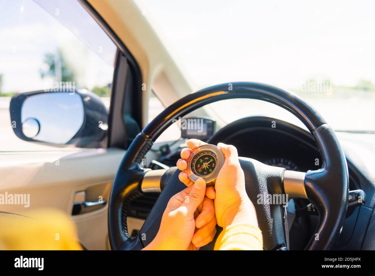 Asian woman inside a car and using compass to navigate while driving ...