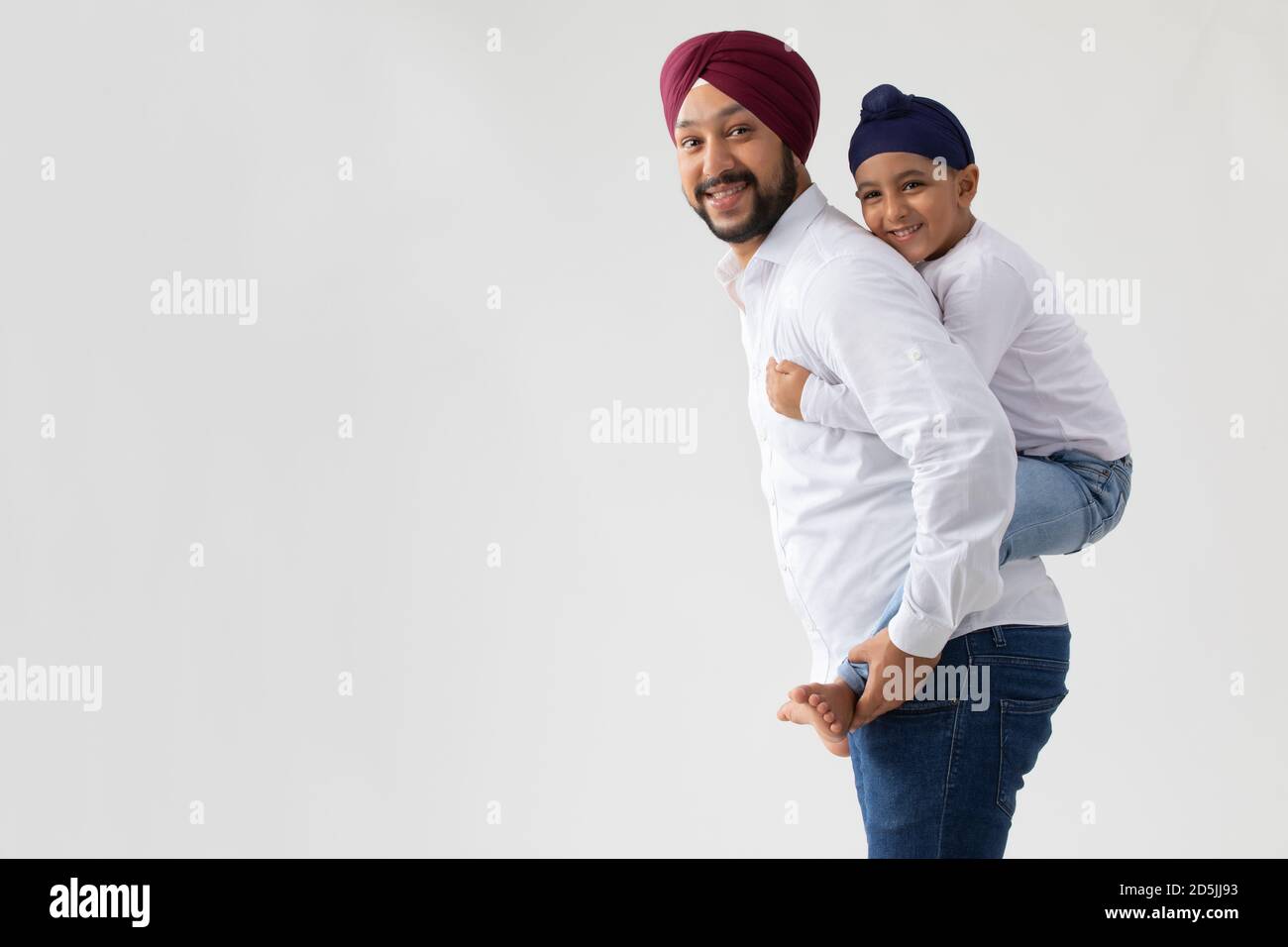 A SIKH FATHER CARRYING HIS SON ON HIS BACK SIMILING AND POSING Stock ...
