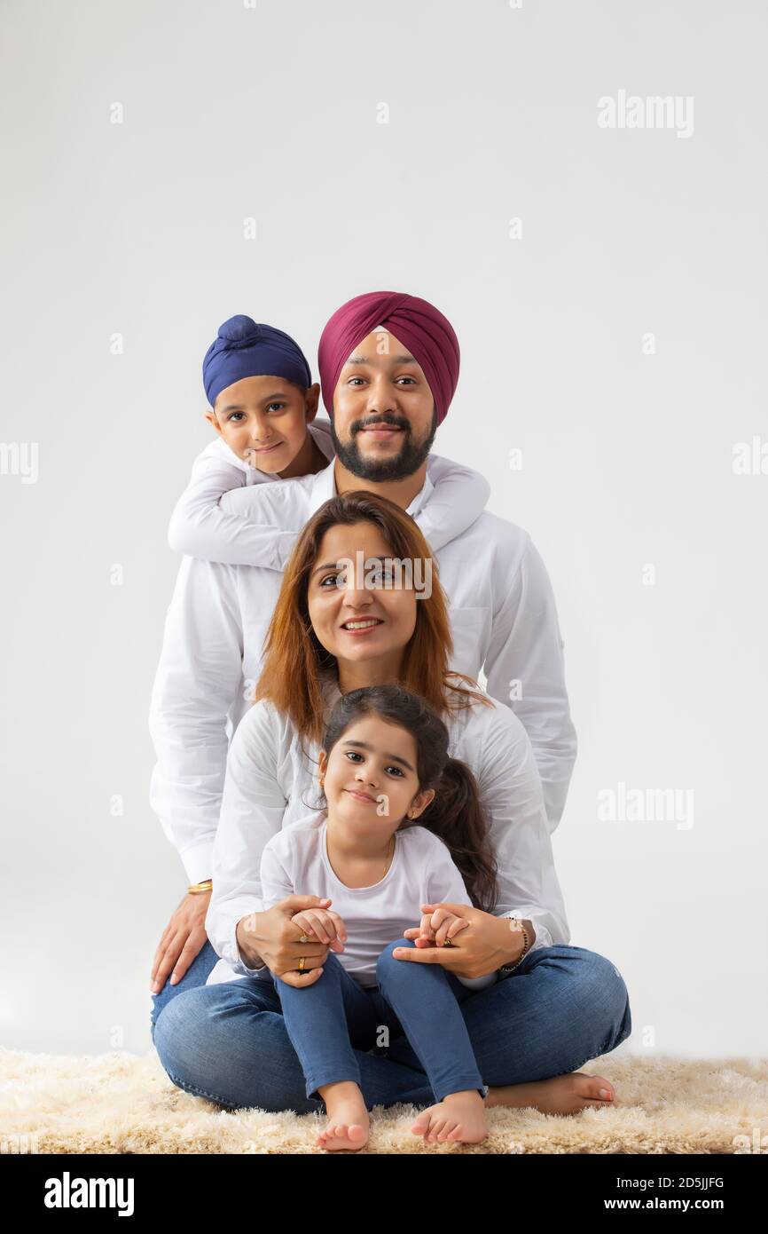 SIKH FAMILY SITTING DOWN ON RUG TOGETHER IN HAPPINESS AND COMFORTABLY ...