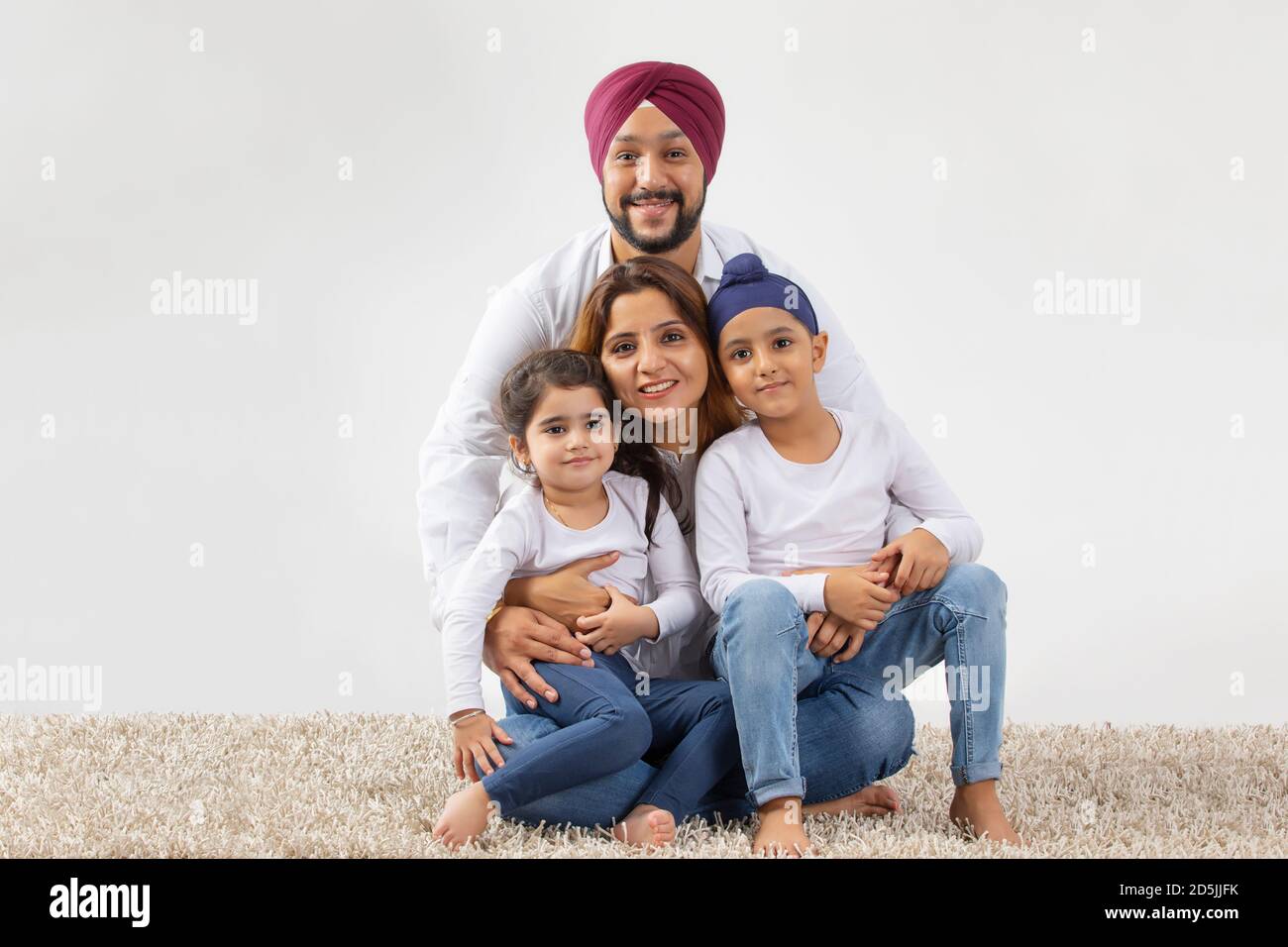 SIKH BOY AND GIRL SITTING ON MOTHER'S LAP AND FATHER HUGGING THEM Stock ...