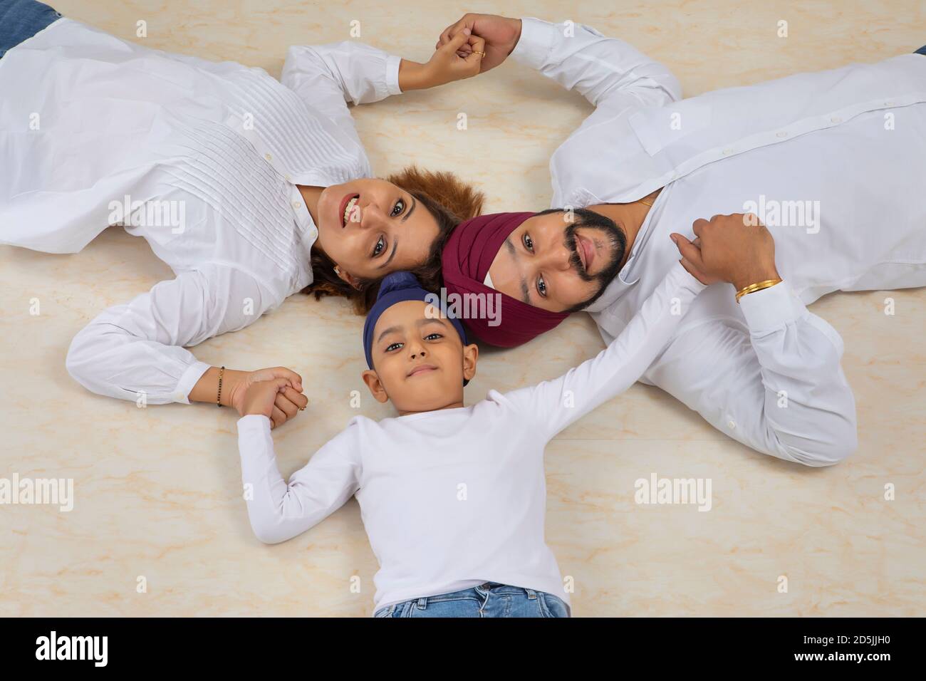 SIKH FATHER MOTHER AND SON HOLDING HANDS TOGETHER AND POSING BY LYING ...