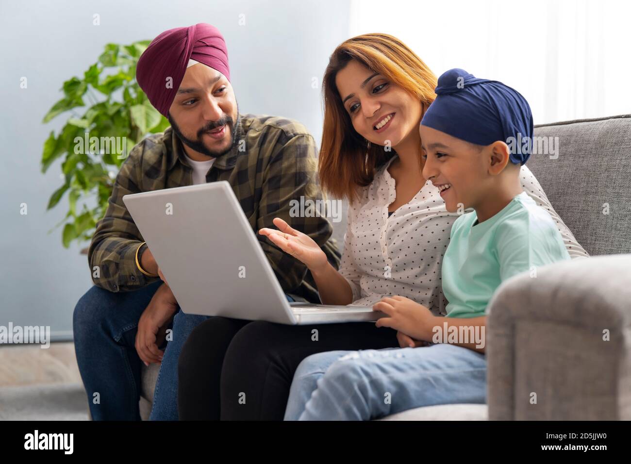 A SIKH SON ENTHUSIASTICALLY LEARNING FROM FATHER AND MOTHER ON A LAPTOP ...