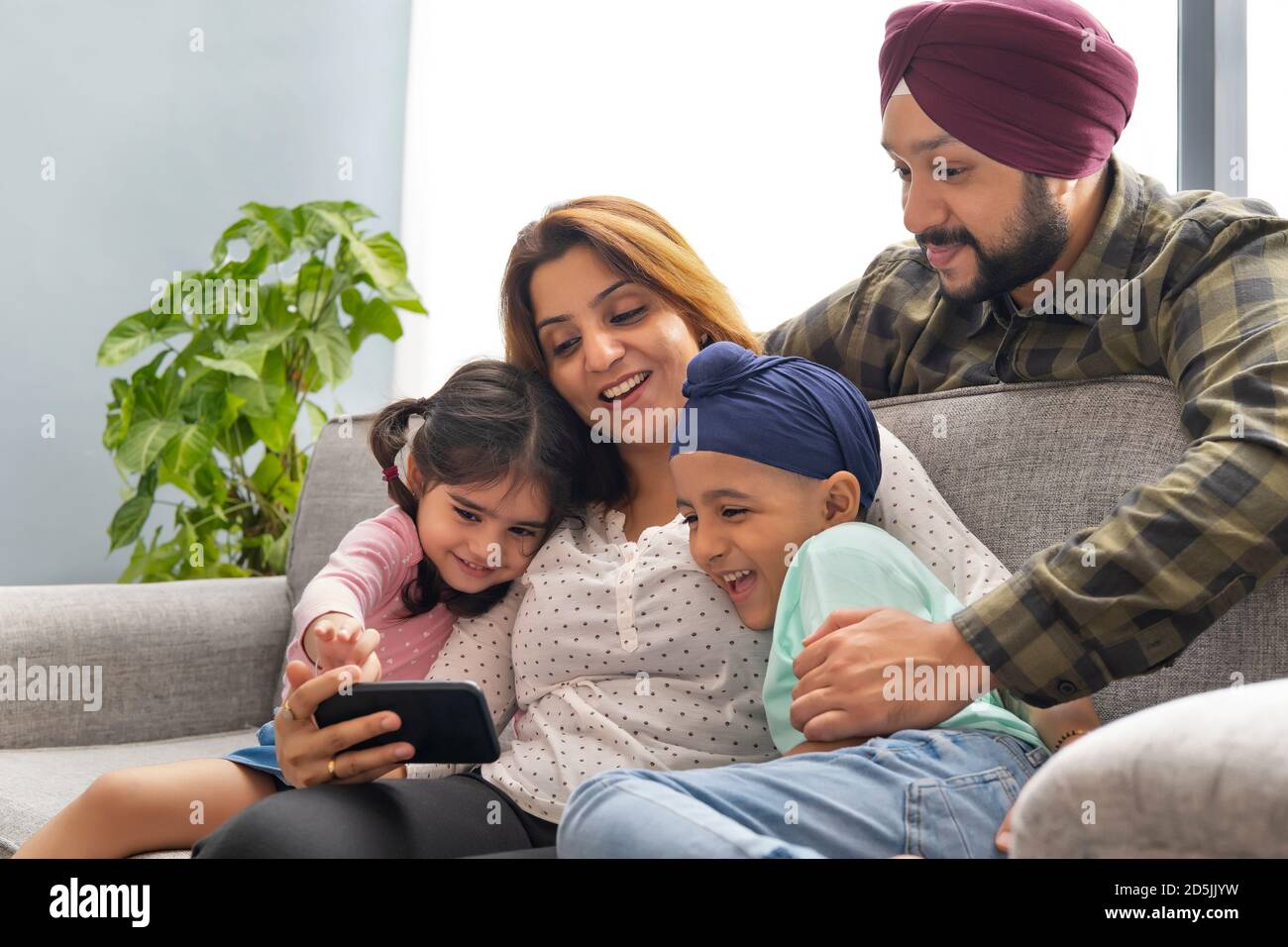 A LITTLE SIKH GIRL POINTING TOWARDS MOBILE HELD BY MOTHER AND BROTHER ...